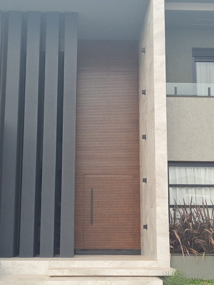 Porta pivotante em ACM amadeirado ripado na horizontal com bandeira ...